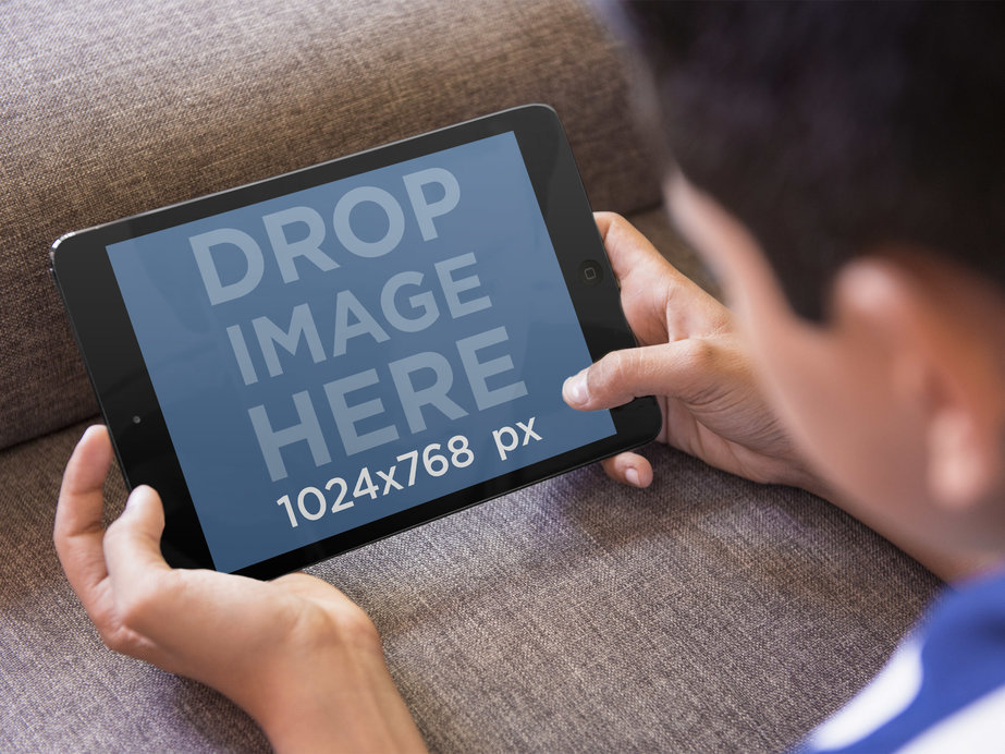 Placeit - Tablet Mockup of Boy Playing With iPad Mini on the Couch