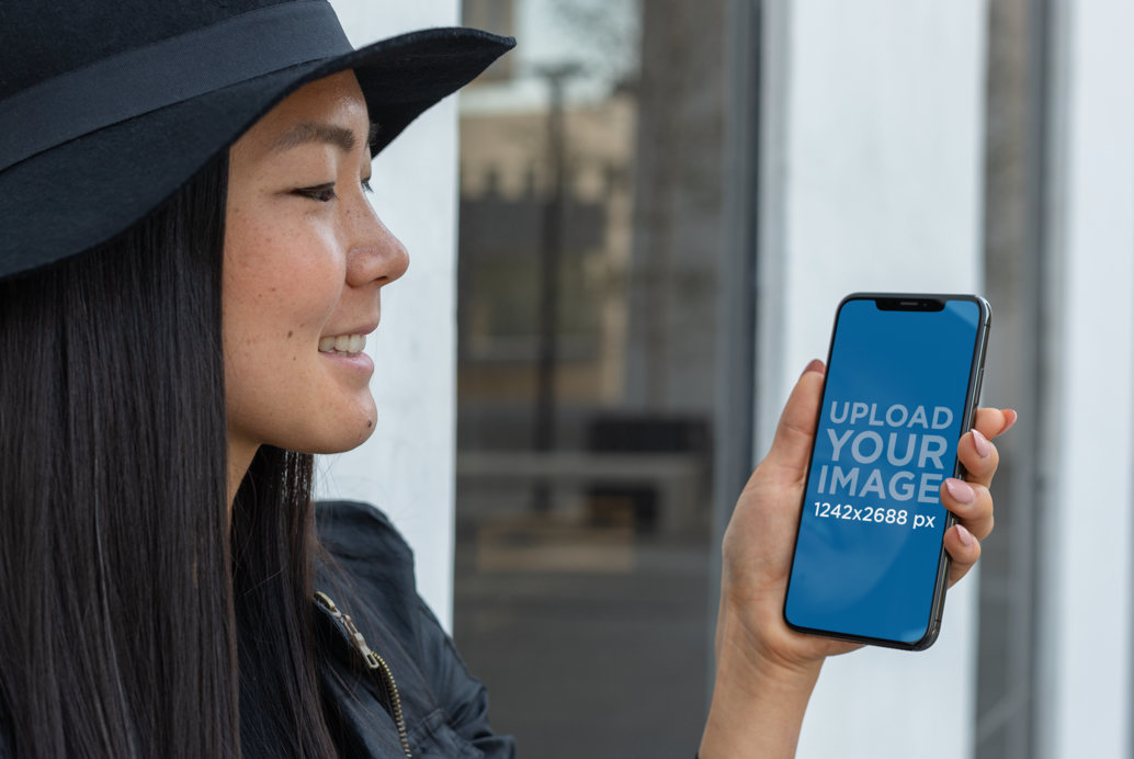 Placeit - Mockup of a Smiling Woman with a Hat Holding Her iPhone 11 ...
