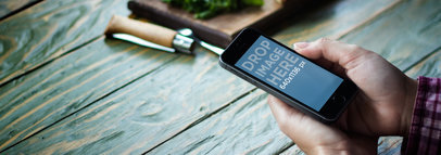Placeit - Mockup of a Man Checking His iPhone at a Bistro Table